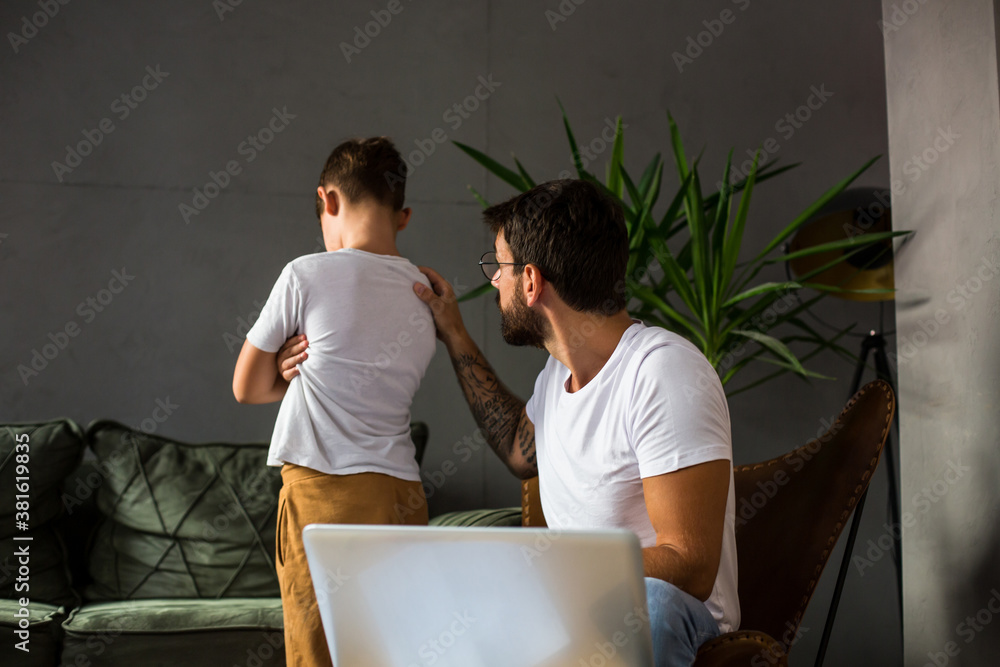 Father and son together in the living room, father explains to son that ...
