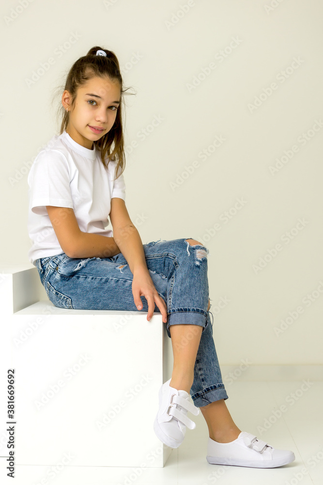 Little girl poses for a magazine in the studio on a white cube. Stock ...