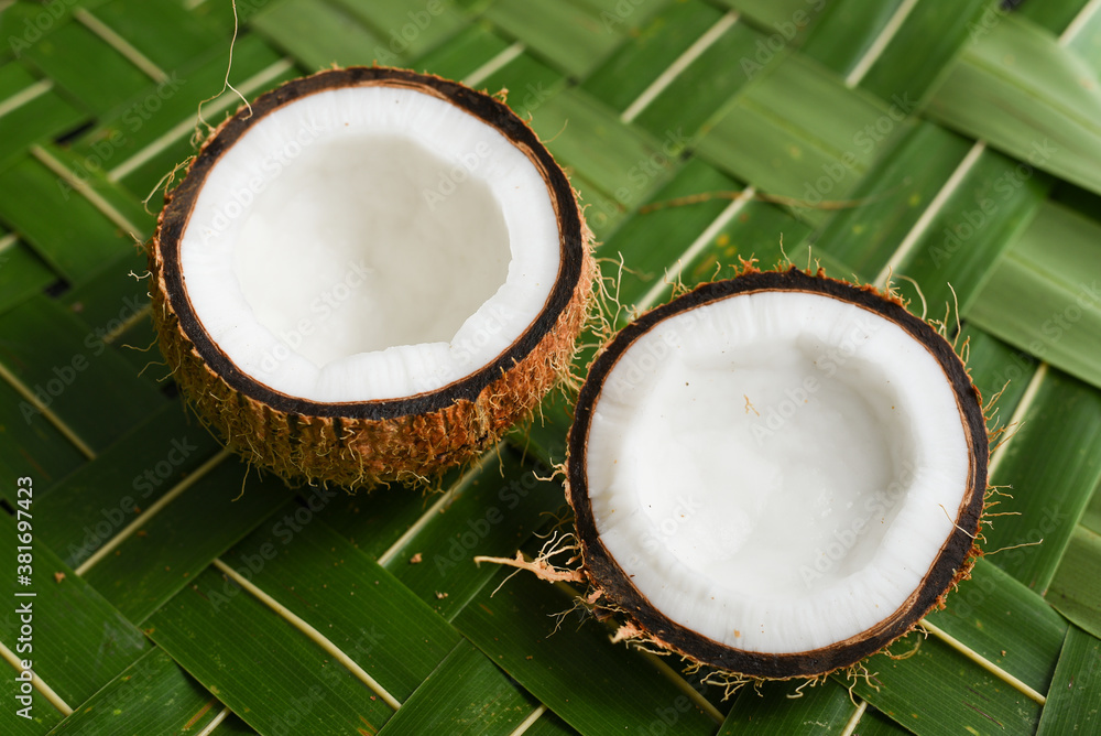Fresh coconut cut open in half from organic farm on green palm leaf ...