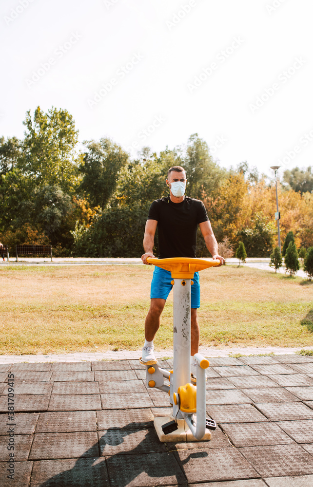 Fit young male caucasian athlete with face mask trains on arm and leg ...
