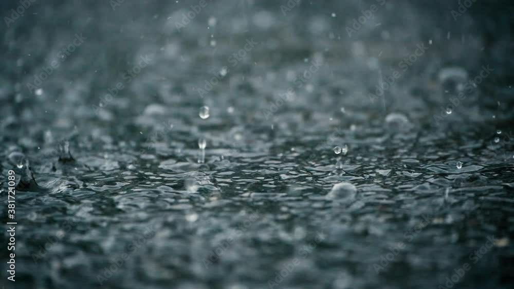 Super slow motion close up of rain hitting a puddle during a suburban ...