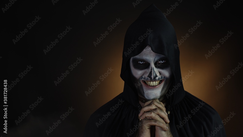 Creepy, crazy man with skeleton makeup in hood making angry faces ...