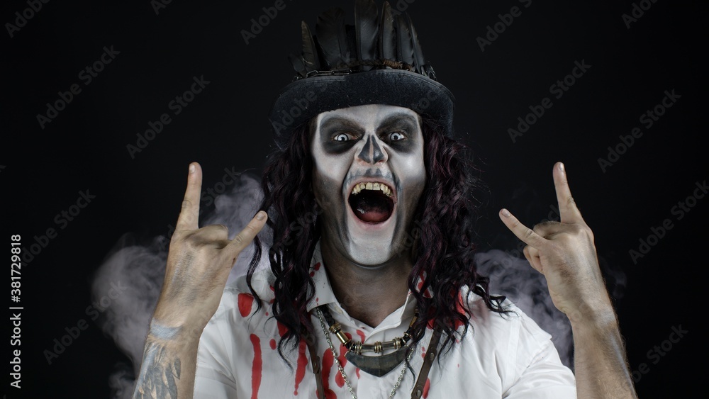 Scary guy in costume of Halloween skeleton in bloody shirt, listening ...