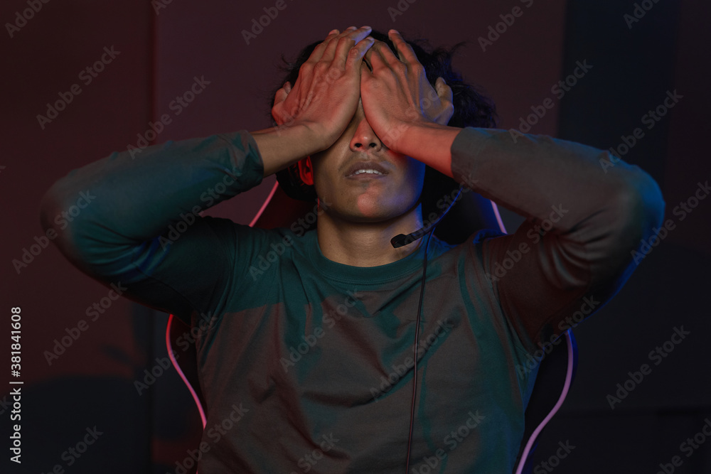 Young computer hacker sitting on chair and rubbing his eyes he tired of ...
