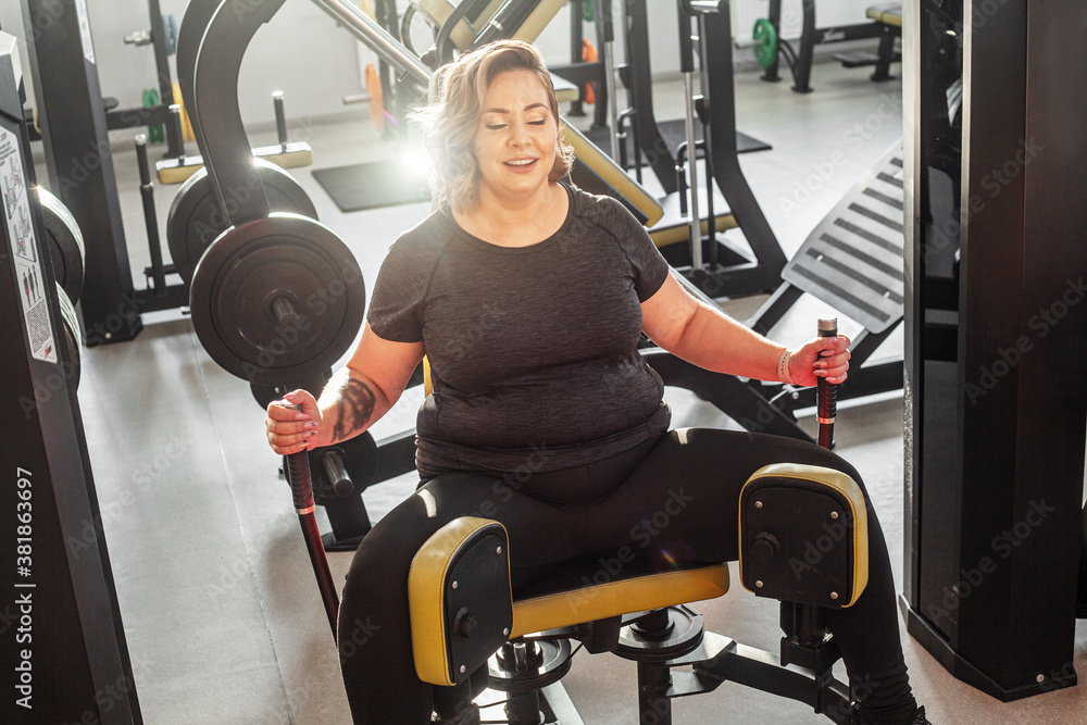 Fat woman fights overweight in the gym, doing heavy fitness exercises ...