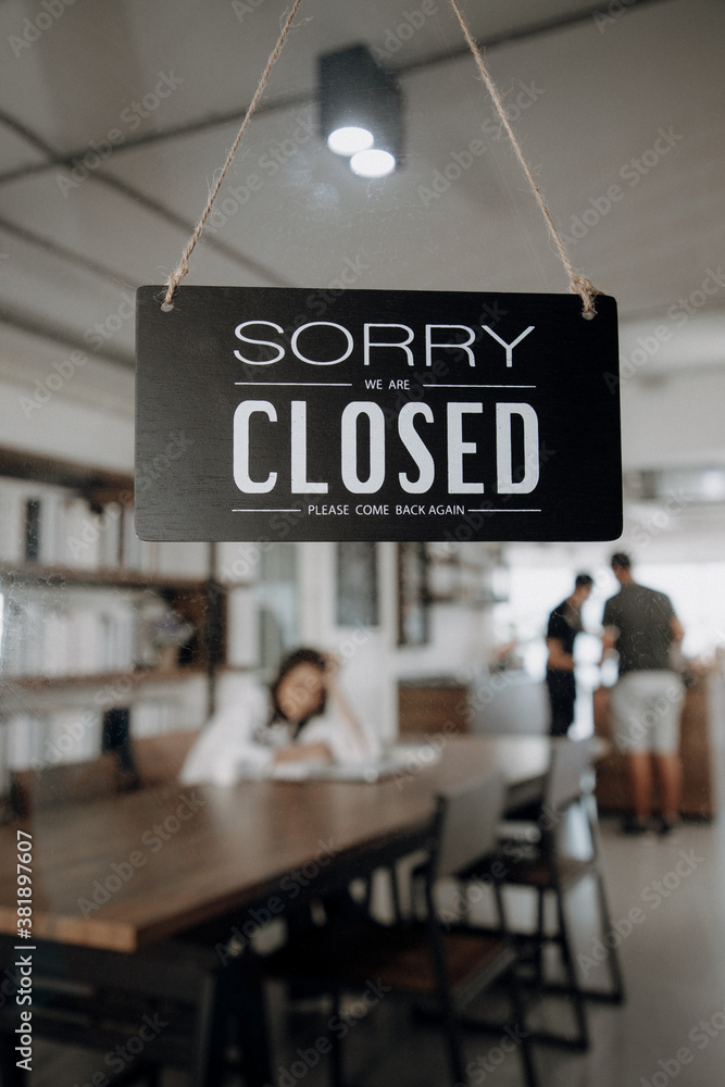Closed sign board through the glass of store window of cafe because due ...