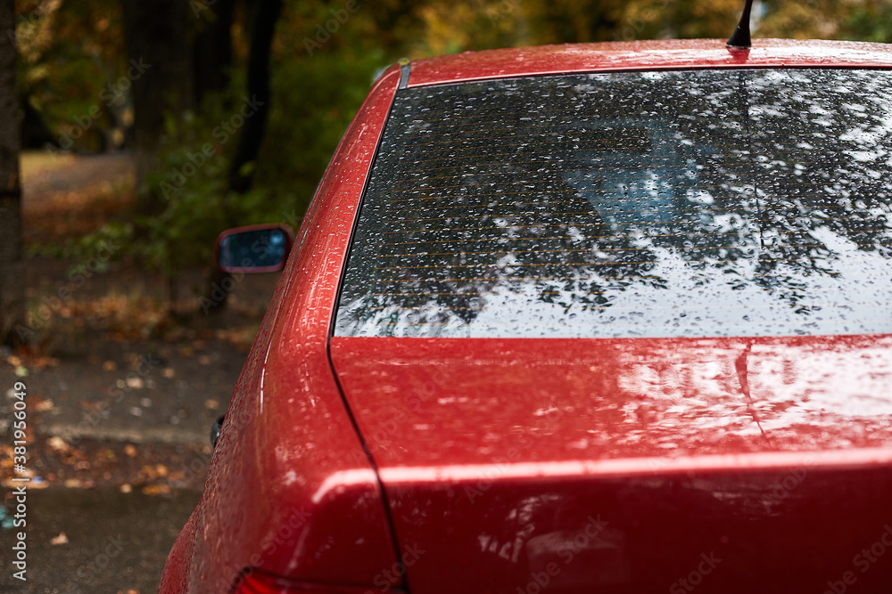 Back window of red car parked on the street in autumn rainy day, rear ...