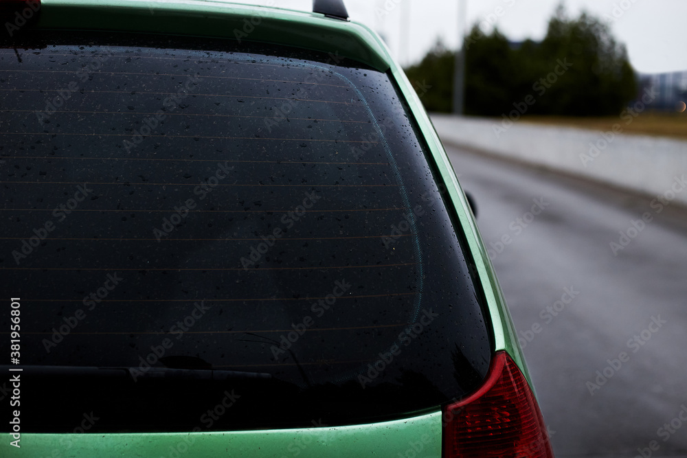 Back window of green car parked on the street in autumn rainy day, rear ...