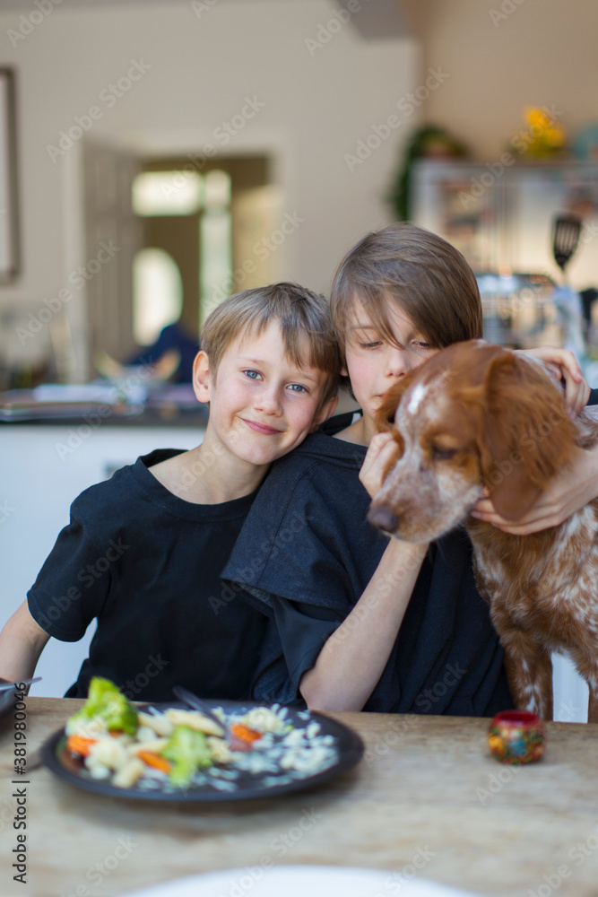 Portrait brothers with dog eating at dining table Stock Photo | Adobe Stock