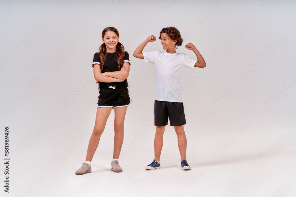 Two teenagers having workout. Happy boy showing his biceps to a cute ...