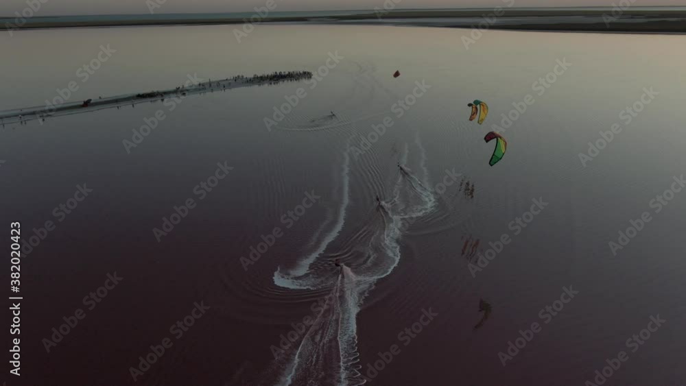 Drone footage of kite surfers gliding on pink water of the lake, nature ...