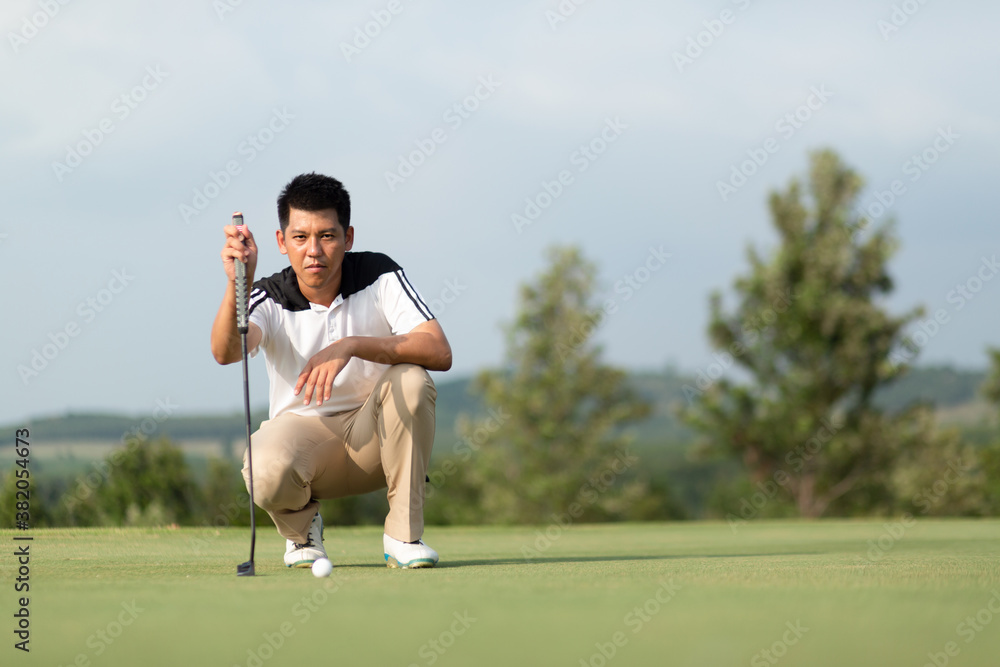 Golfers sit on the green to see the direction of putting golf balls ...