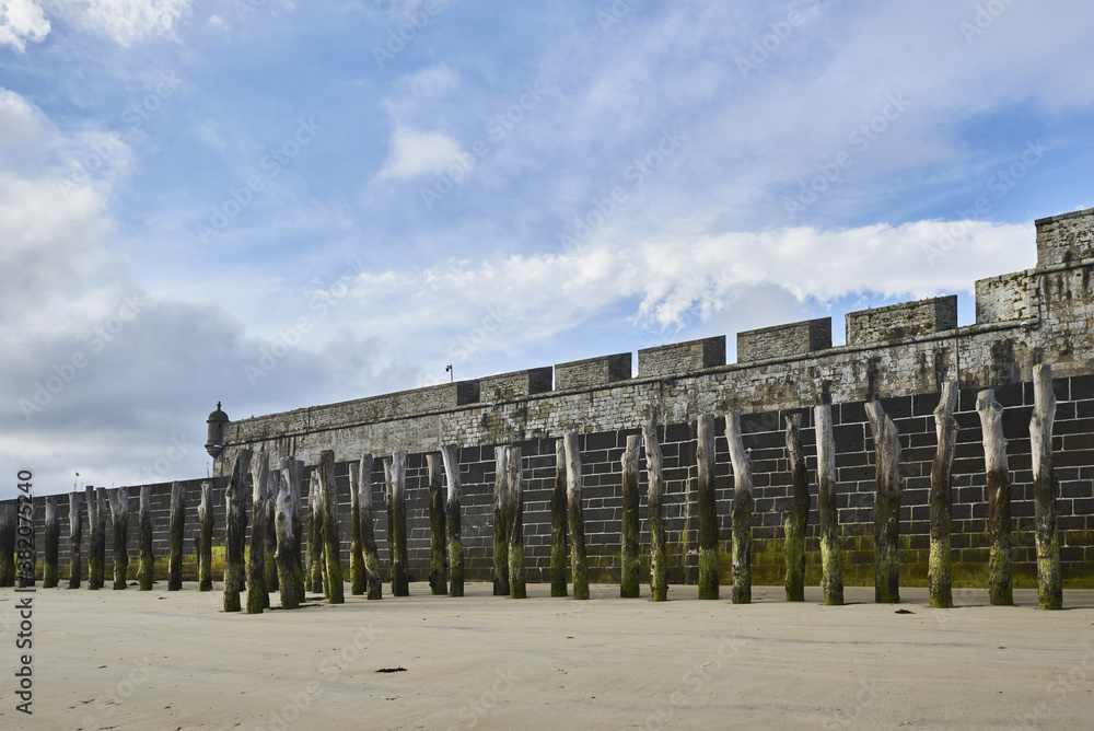 Poster Wooden Poles and rampart on the beach at low tide in Saint Malo ...