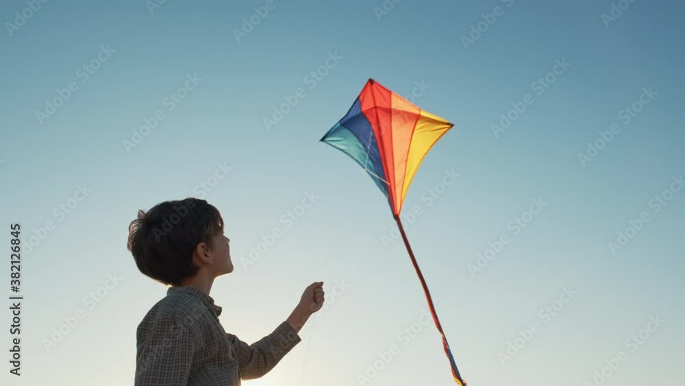 Happy boy launches bright kite into sky on mown wheat field, playing ...