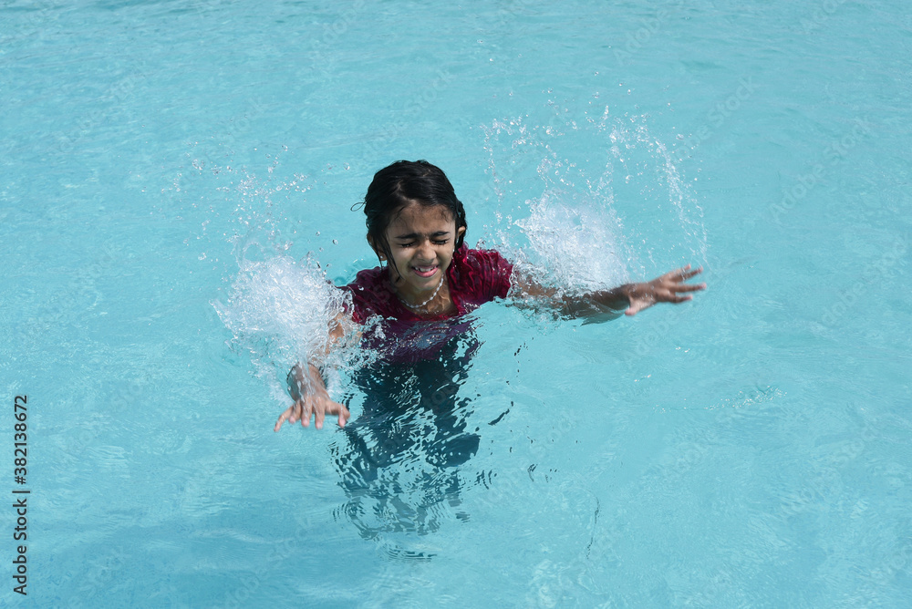 Small Indian girl swimming or learning to swim, splashing water in ...