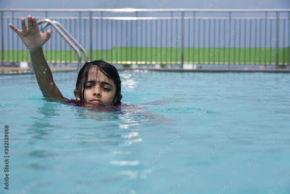 Small Indian girl swimming or learning to swim, splashing water in ...