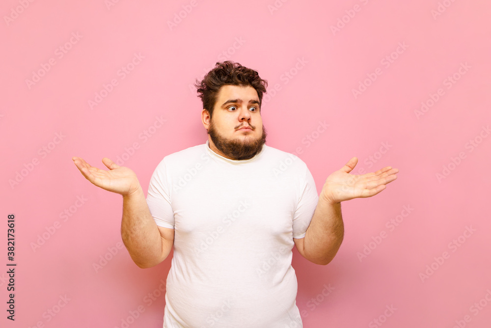 Portrait of puzzled fat man with shocked face on pink background ...