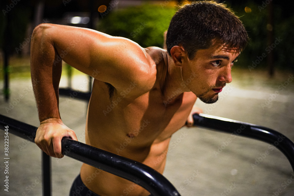 Young shirtless guy training at night street workout. Doing dips. Stock ...