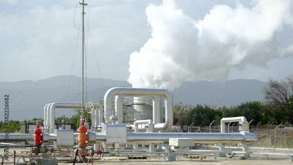Geothermal station with steam and pipes in the rainforest. Billowing ...