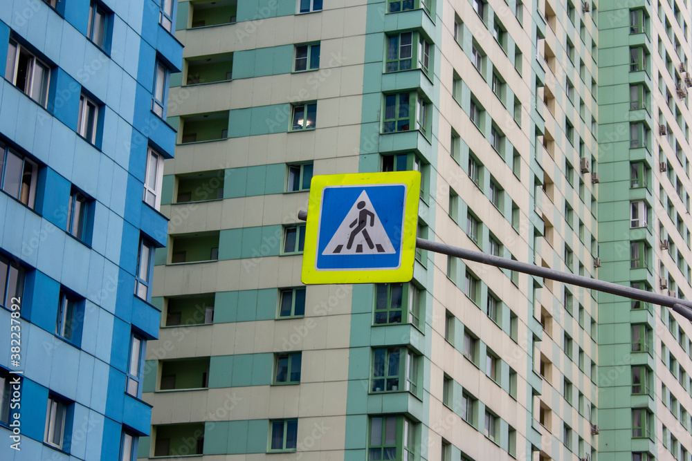 Road sign of a pedestrian crossing against the background of multi ...