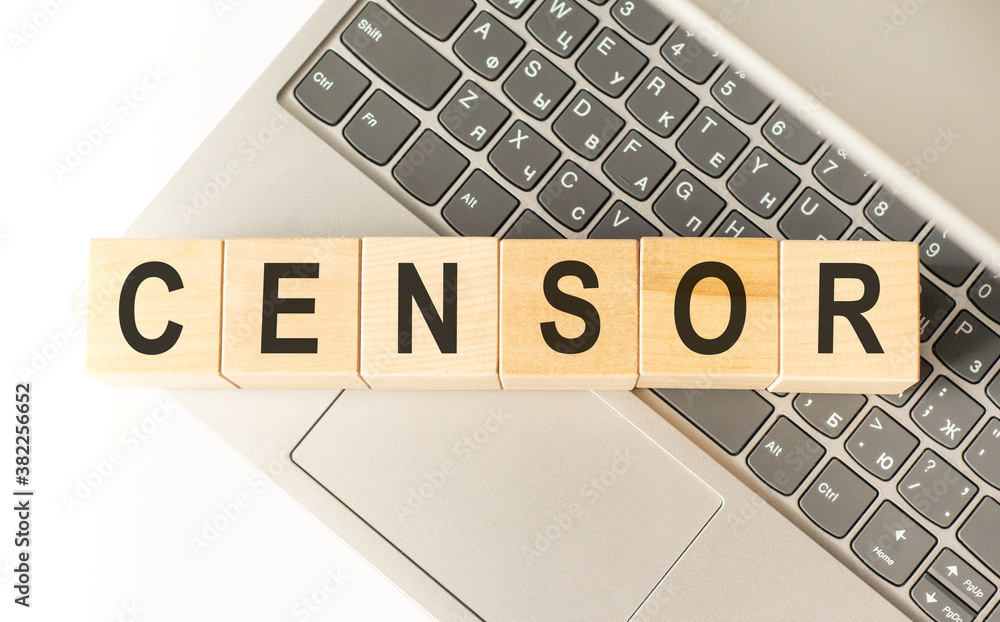 Word censor. Wooden cubes with letters isolated on a laptop keyboard ...