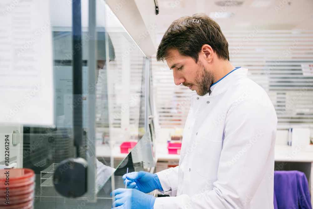 Side view of man in white robe and gloves working in modern ...