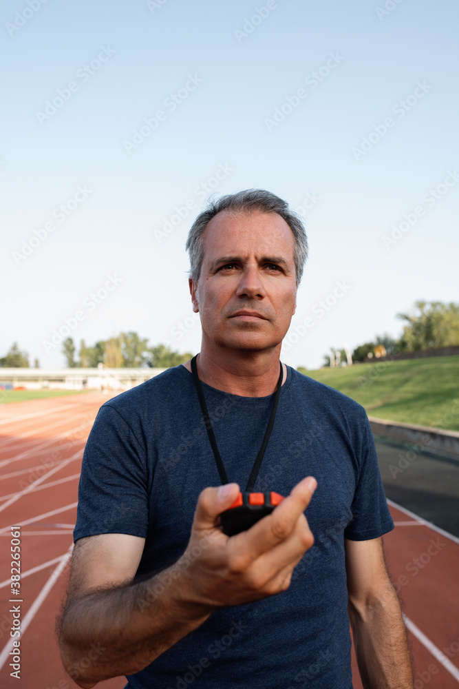 Serious coach with timer on stadium Stock Photo | Adobe Stock