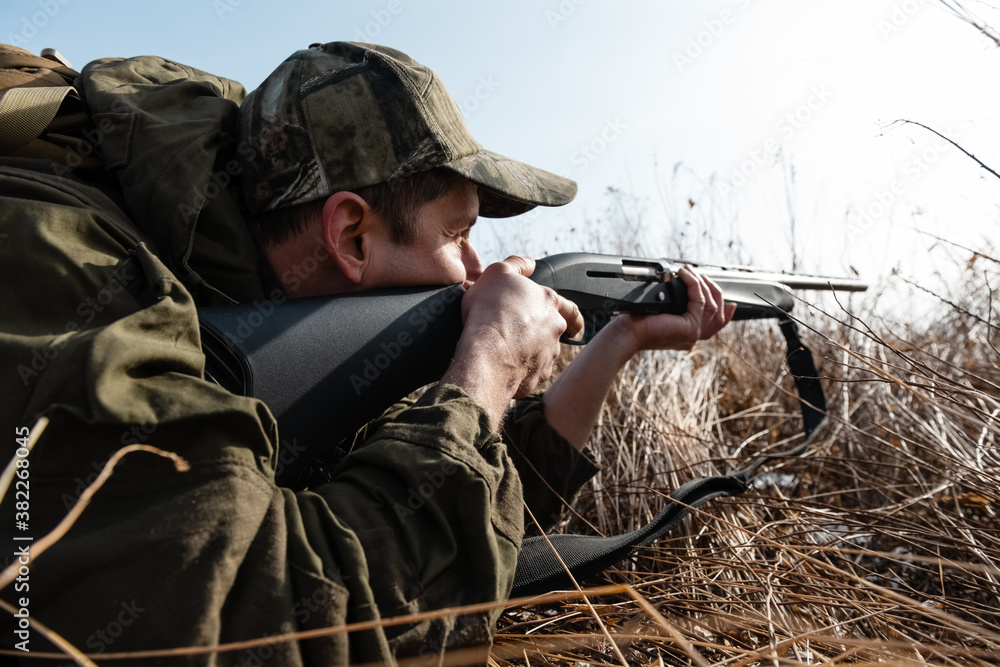 Focused huntsman firing gun in grass Stock Photo | Adobe Stock