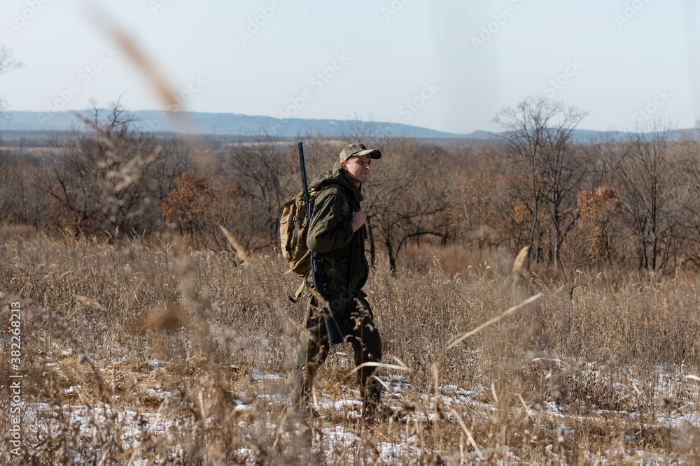 Male hunter walking in field Stock Photo | Adobe Stock