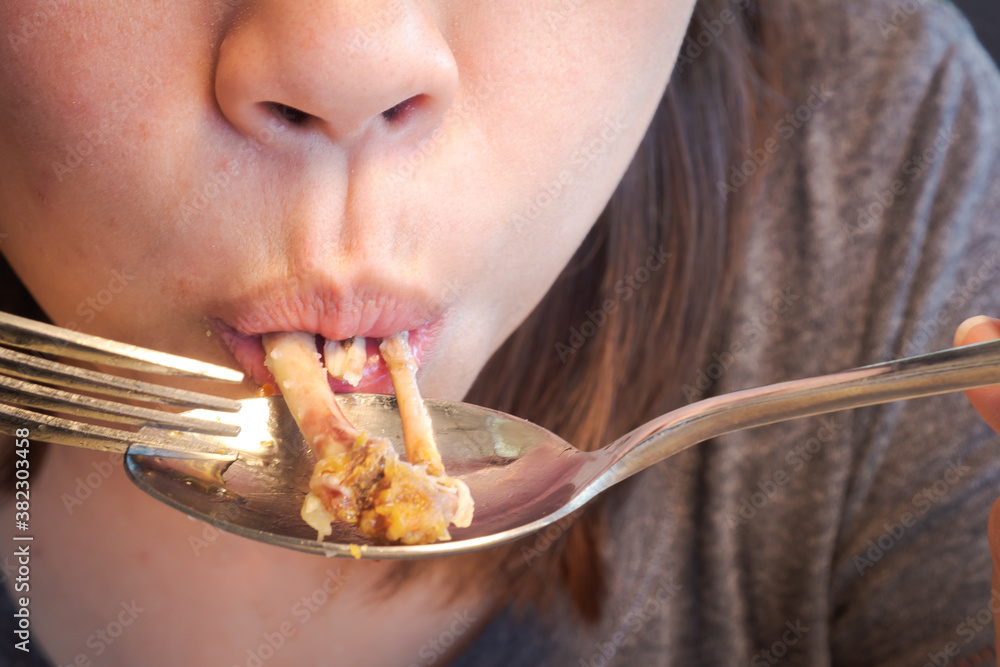 Mouth shot of an Asian woman using chop and fork to eat crispy fried ...