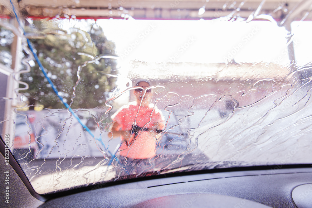 Woman washing her car with high pressure sprayer at self-serve car wash ...