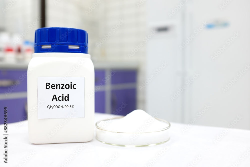 Selective focus of a bottle of pure benzoic acid chemical compound beside a petri dish with ...