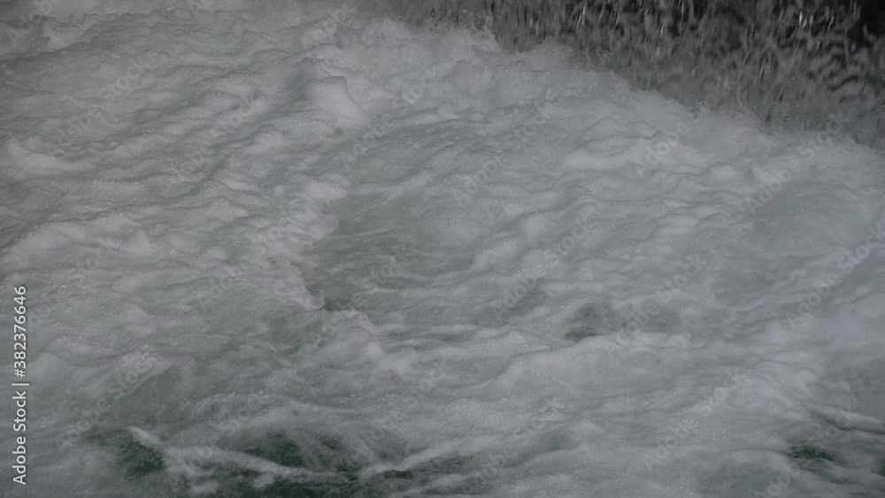 Close up view of Alpine river waterfall base. Stream flowing over man ...