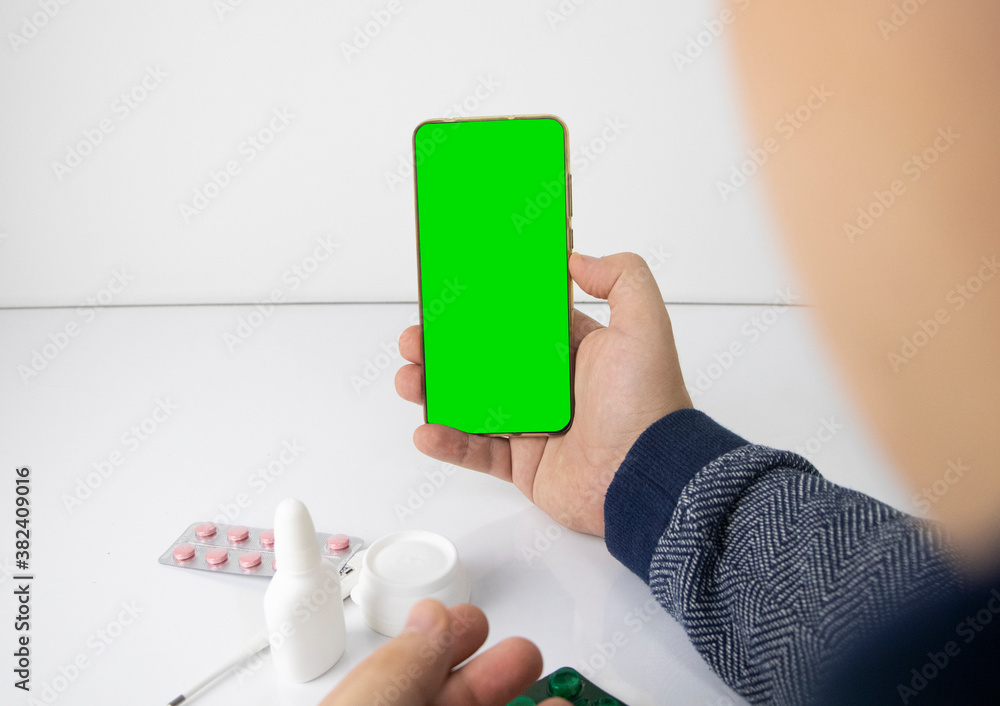 The sick man looks at the smartphone. The gadget has a green screen ...