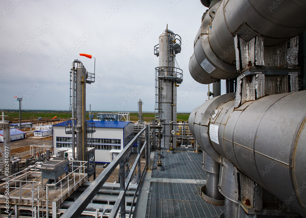 Distillation towers with orange weather vane. Heat exchangers on ...