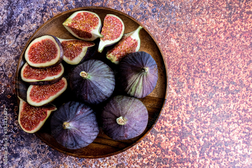 Whole figs and one fig sliced in half on top of a teak garden table ...