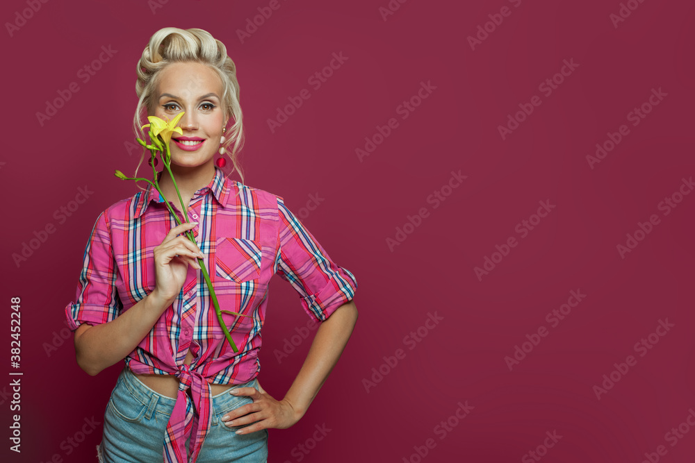 Pin-up woman with makeup and retro hairstyle holding flowers on pink ...