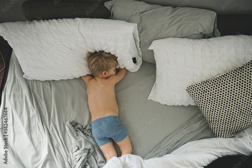 Boy napping in parent's bed in boxer briefs Stock Photo | Adobe Stock