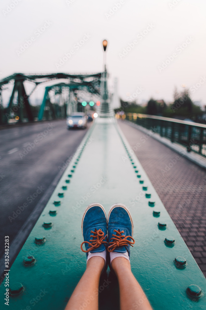 Woman making picture of her own feet while sitting on the bridge over ...