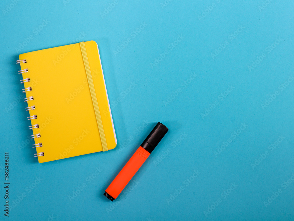 notepad and pen A yellow notepad and an orange marker lie on the left ...