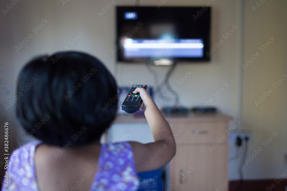 Little girl watching TV and changing channel with remote control Stock ...