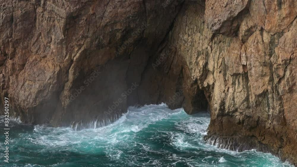 Sea waves enter a cave in the rock and form large splashes of water, 4k ...