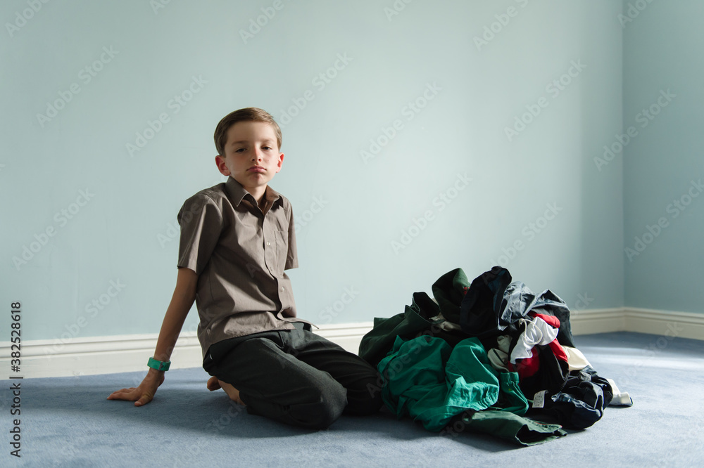 Boy looks unimpressed at a pile of dirty laundry Stock Photo | Adobe Stock