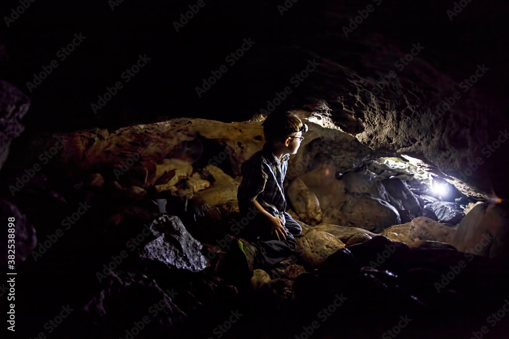 Little Boy Exploring a Dark Natural Cave With A Headlight Stock Photo ...