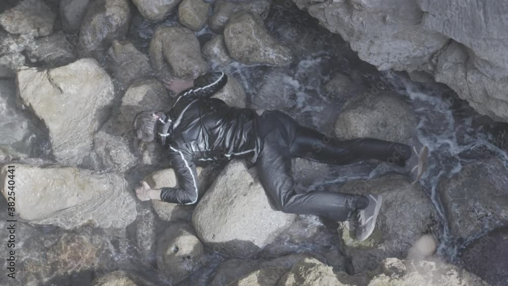 Dead man on rocks. Stock. Top view of dead body of man lying face down ...