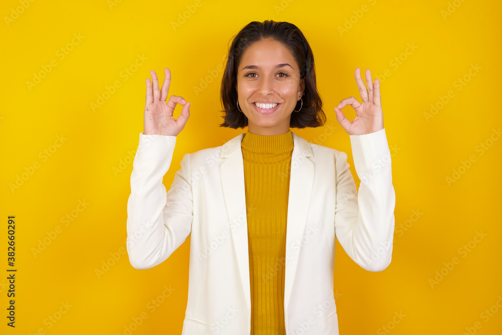 Glad attractive woman shows ok sign with both hands as expresses ...
