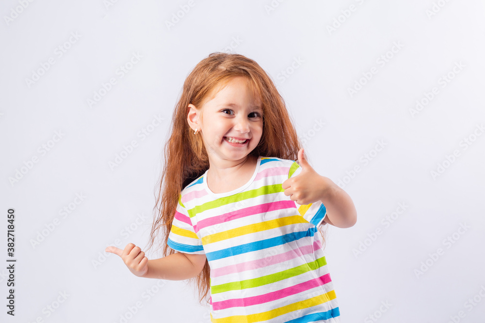 little girl with long red hair is smiling in a multi-colored t-shirt on ...