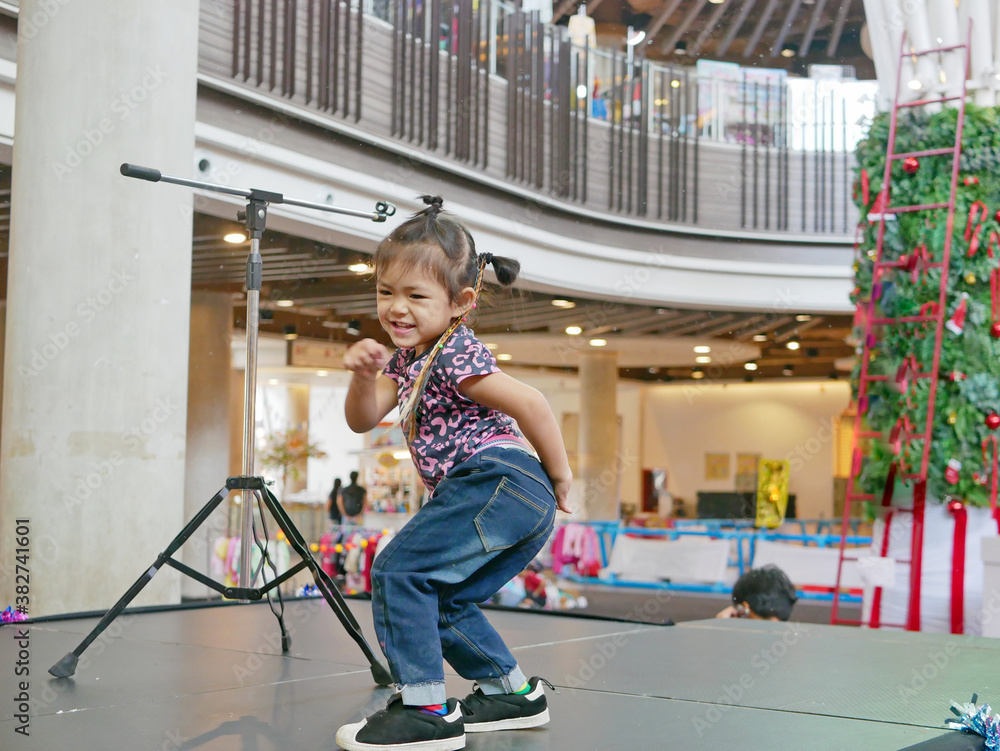 Little baby girl, 2 years old, enjoys dancing on a setting-up consert ...