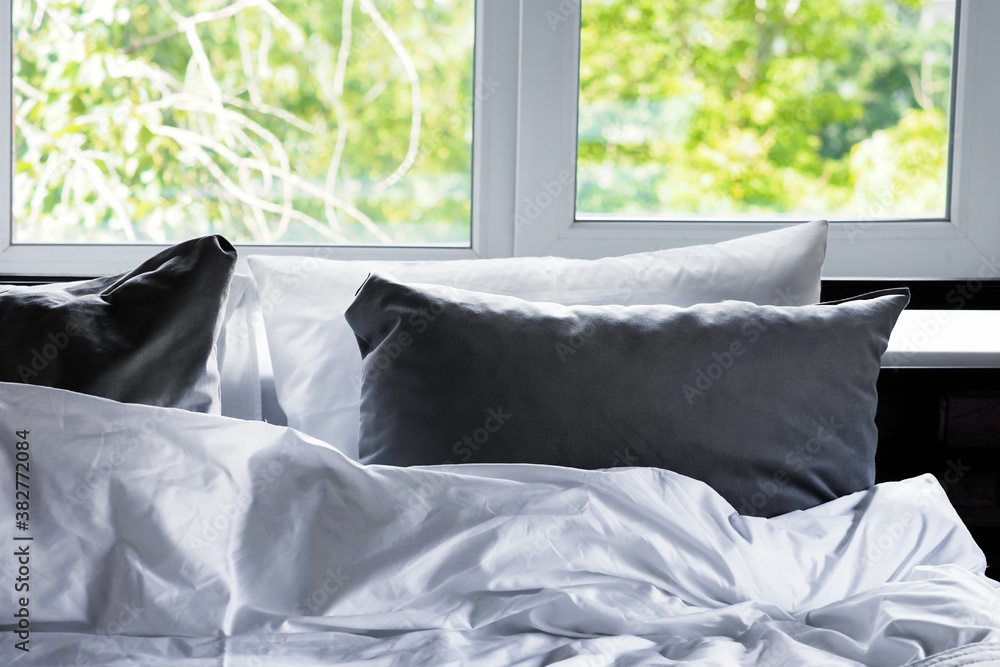Bed by the window in the bedroom, lots of pillows, bedroom interior ...