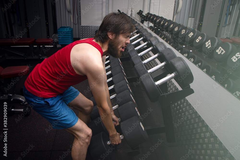 Weak man tries to lift heavy dumbbell, wants to be strong and fit ...